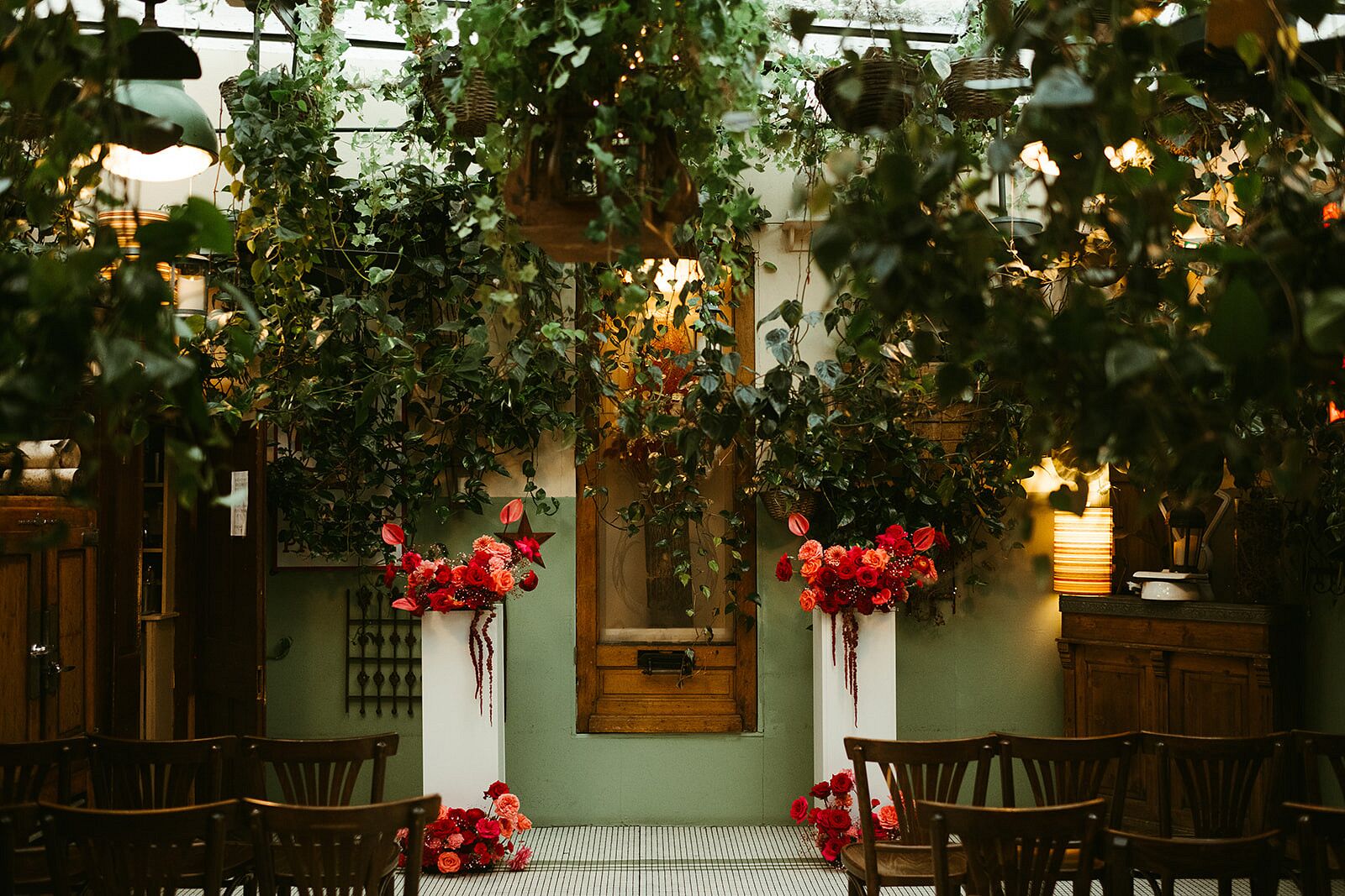 Hanging Greenery and Columns With Pink and Red Floral Arrangements
