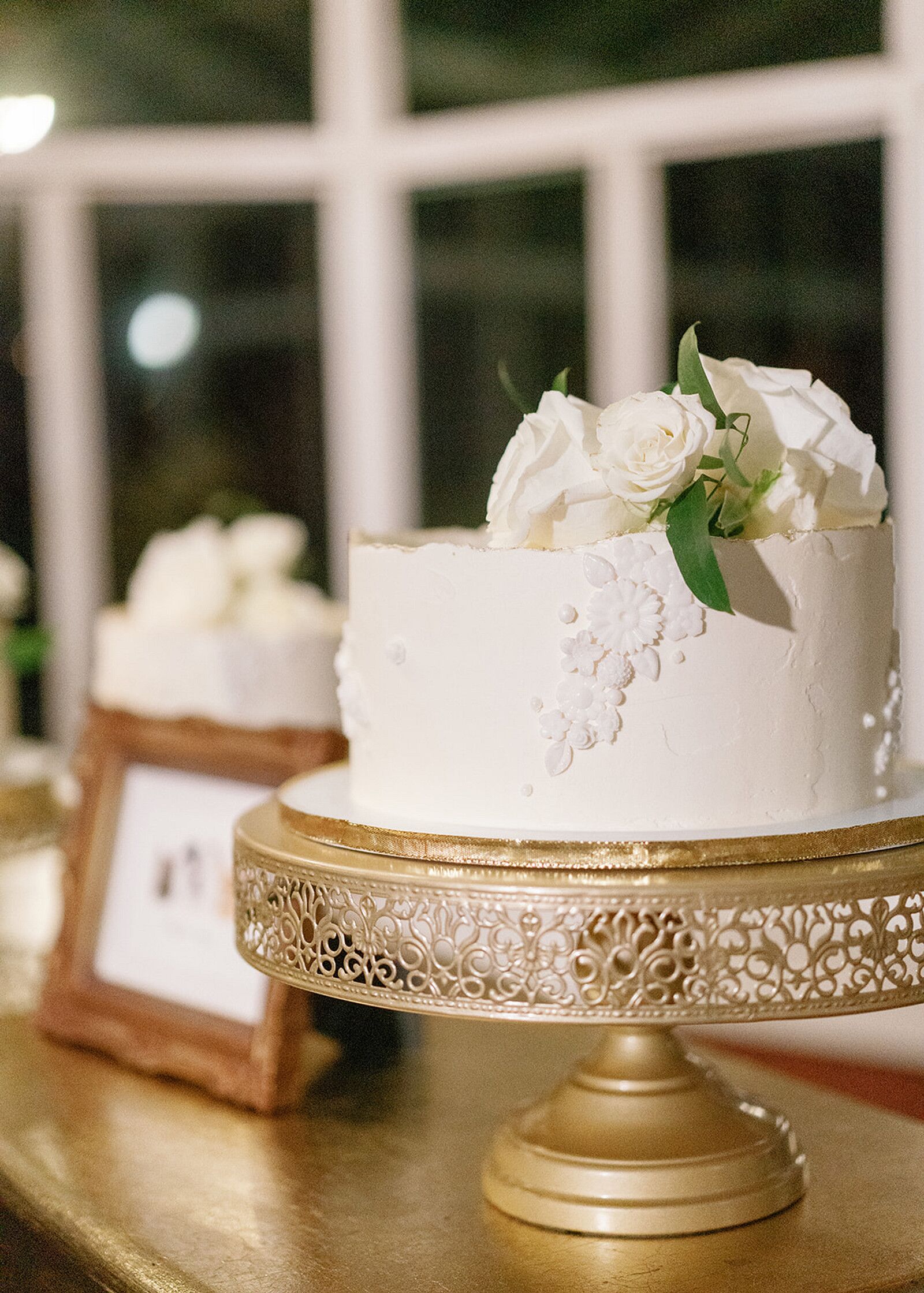 Small, Single-Tier Wedding Cake With White Floral Details on a Gold ...